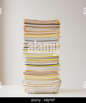 A very tall stack of paperwork in color folders. A Computer mouse and ...