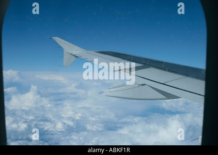 Airplane wing above clowds seen through window Stock Photo - Alamy