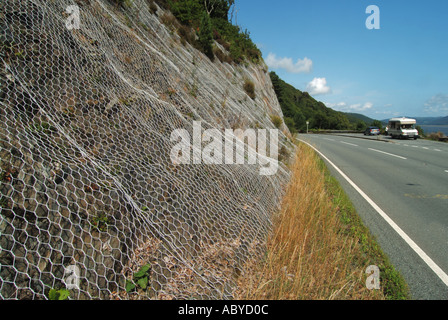 roadside cliff covered in wire netting to help contain rock debris ...