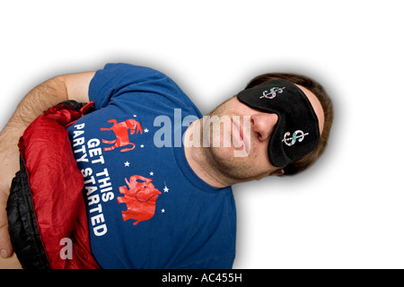 Young man in sleeping mask turning off alarm clock while lying on bed ...