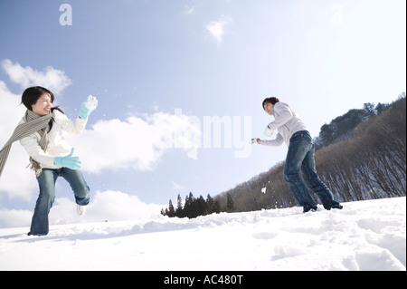 Young man, woman playing, throwing snowballs in winter snowstorm, storm ...