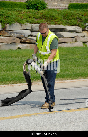 Road workers pour tar in the cracks of street pavement Stock Photo - Alamy