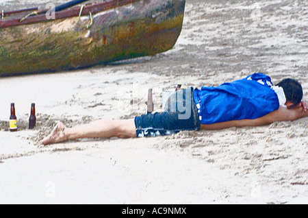 a drunk tourist passed out on the beach near a canoe in Puerto Vallarta ...