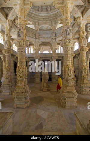 A Jain priest walking through the forest of intricately carved pillars ...