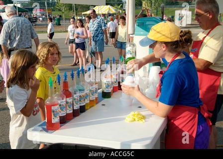 Vendor sells flavored snow cones to adults and children at a carnival ...