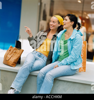 Two cheerful young women laughing and splashing in the clear blue water ...