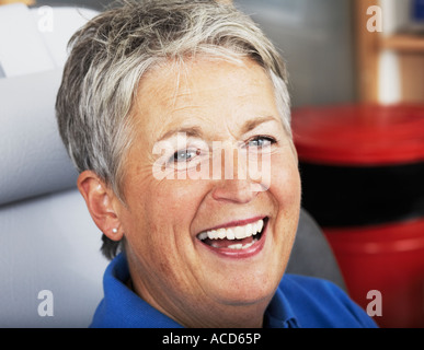 Middle age grey-haired woman drinking coffee and using touchpad at home ...