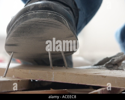 Wrong footwear on workers feet on building site where projecting nails ...