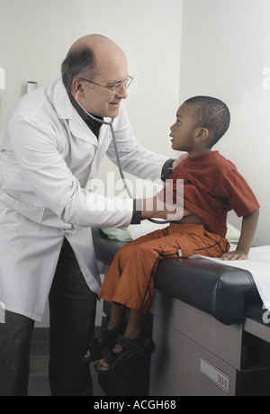 Young boy having check-up in doctor's office, doctor looking in boy's ...