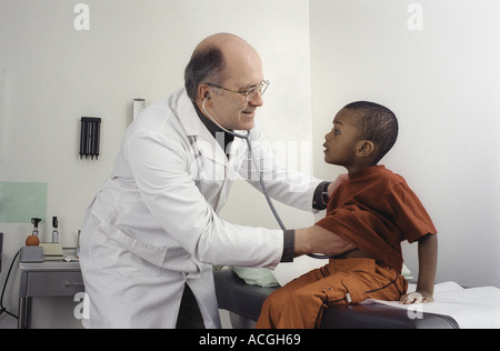 Young boy having check-up in doctor's office, doctor looking in boy's ...