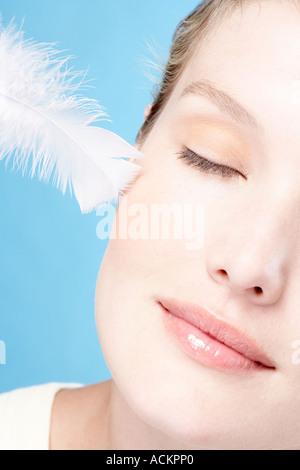 Close up of a feather touching a young woman s face Stock Photo - Alamy