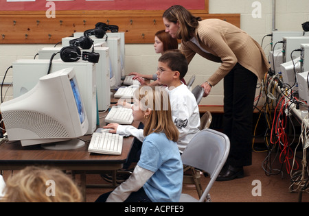 Kids with teacher using computers in classroom Stock Photo - Alamy