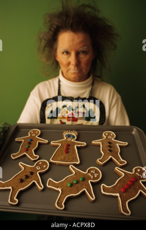Lady with mad exhausted look on face holding gingerbread cookie sheet ...