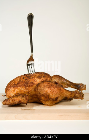 A fork stuck in a roast chicken Stock Photo - Alamy