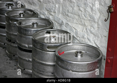 A line of empty aluminum beer kegs against a white stuccoed wall of a ...