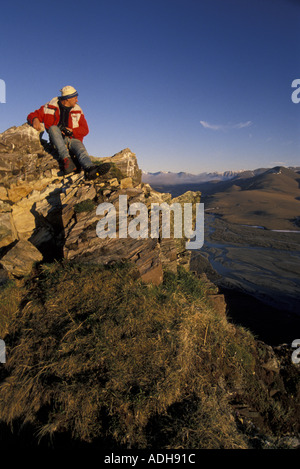 A hiker resting on a rock outcrop near Glyder Fach in the Snowdonia ...