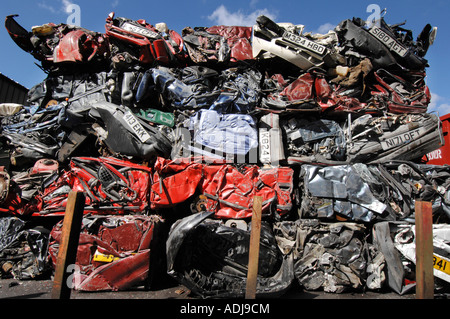 Cubes of crushed cars stand in a huge pile as a crane lifts a Fiat ...