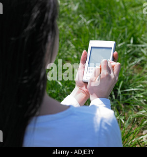 a woman doing something with a PDA on the grass Stock Photo - Alamy