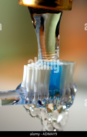 Toothbrush under running water from a steel tap Stock Photo - Alamy