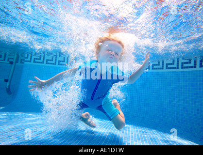 Young boy holding breath underwater in sunny swimming pool on vacation ...