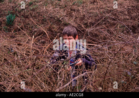 Young boy cutting brambles in overgrown garden Stock Photo - Alamy