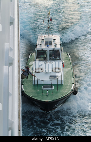 Aerial view of a pilot boat alongside a large container ship in a busy ...