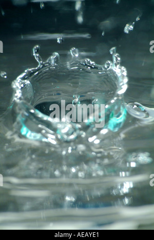 water droplet hitting surface of water and creating a reactive shape ...