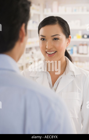 Chinese young man working at pharmacy drugstore thinking looking tired ...