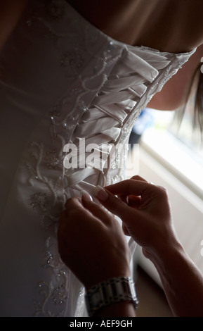 bride being laced up into her wedding dress on her wedding day by her ...