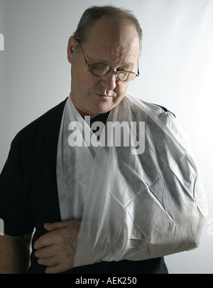 Sad elderly man with a broken arm sitting on a medical bed isolated on ...