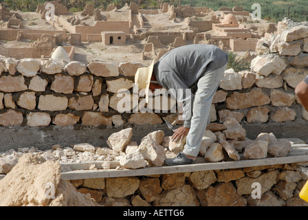 workman building a wall of a new developement overlooking Old Tamerza ...