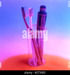 Plastic toothbrushes in glass holder, tube of toothpaste and towels on ...