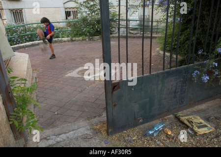 A boy seen playing foot ball in front of a graffiti of famous football ...