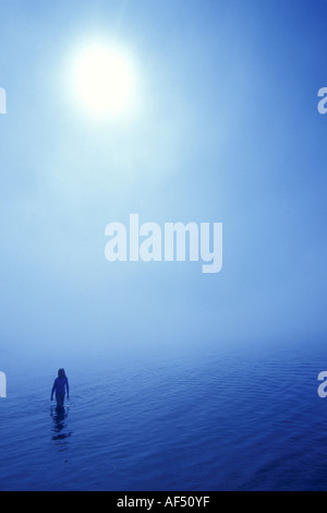A scene of people wading in the sea, with a fisher using a hand net and ...