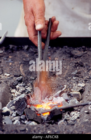 Blacksmith forging a knife out of the hot metal using a hammer ...
