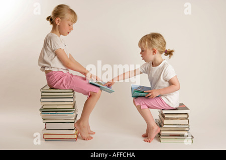 Two girls sitting on pile of giant books in the park, back view Stock ...