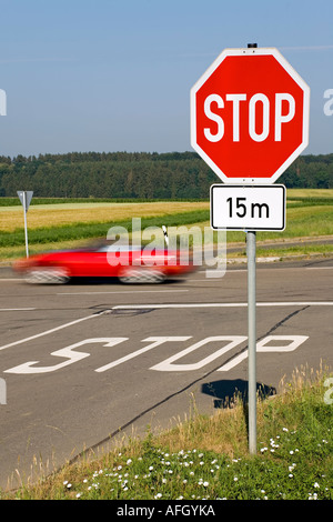 a car passes a crossing with a stop sign another car has to stop Stock ...