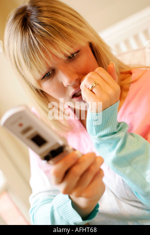 Worried girl reading phone message sitting on a couch in the night at ...