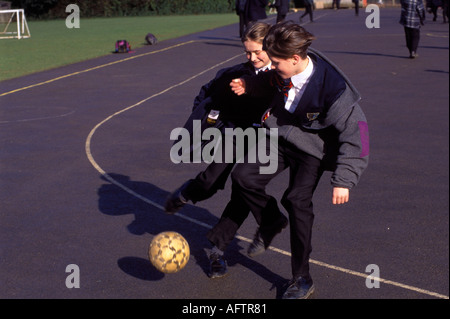Schoolboys playing football on a school playing field at lunchtime ...