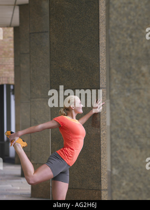 Woman stretching against a pillar Stock Photo - Alamy