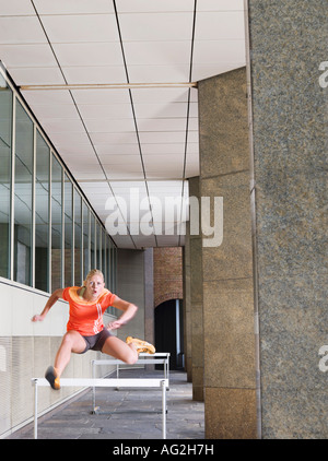 Woman jumping hurdles outside building Stock Photo - Alamy