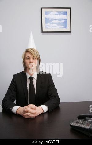 Businessman wearing a dunce cap Stock Photo - Alamy
