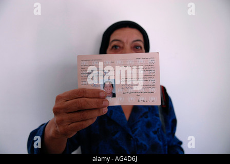 An Iraqi refugee shows her Asylum Seeker card issued by UNHCR in Amman ...