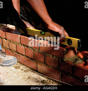 Mason checking level of a brick wall Stock Photo - Alamy