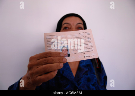 An Iraqi refugee shows her Asylum Seeker card issued by UNHCR in Amman ...