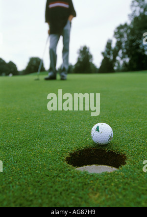 Ball rolling into the hole Stock Photo - Alamy
