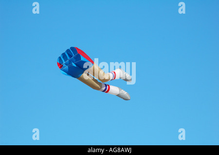 kite or balloon of lower half of a body flying alone against a blue sky ...