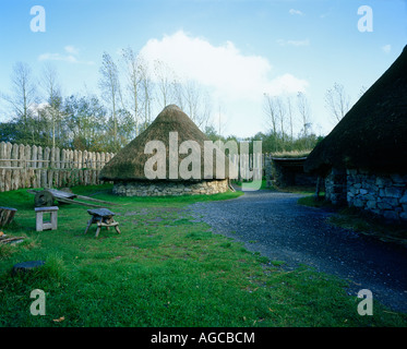 A mud hut with conical thatch roof in a clearing surrounded by banana ...