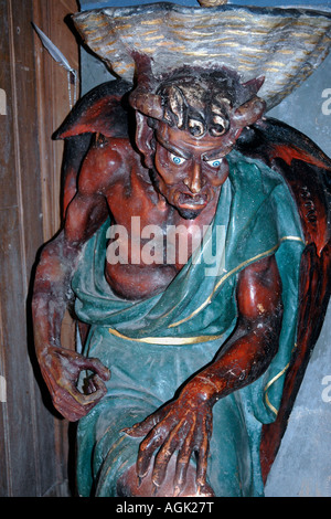 A startling devil holds the holy water basin within the doorway of ...