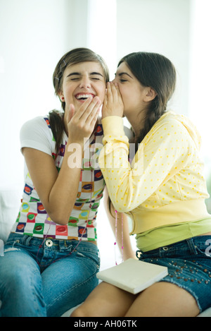 Young woman sniggering or giggling into her hand in a close up cropped ...